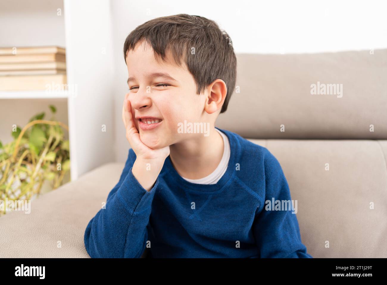 Stressed child complaining suffering toothache sitting on a couch at ...