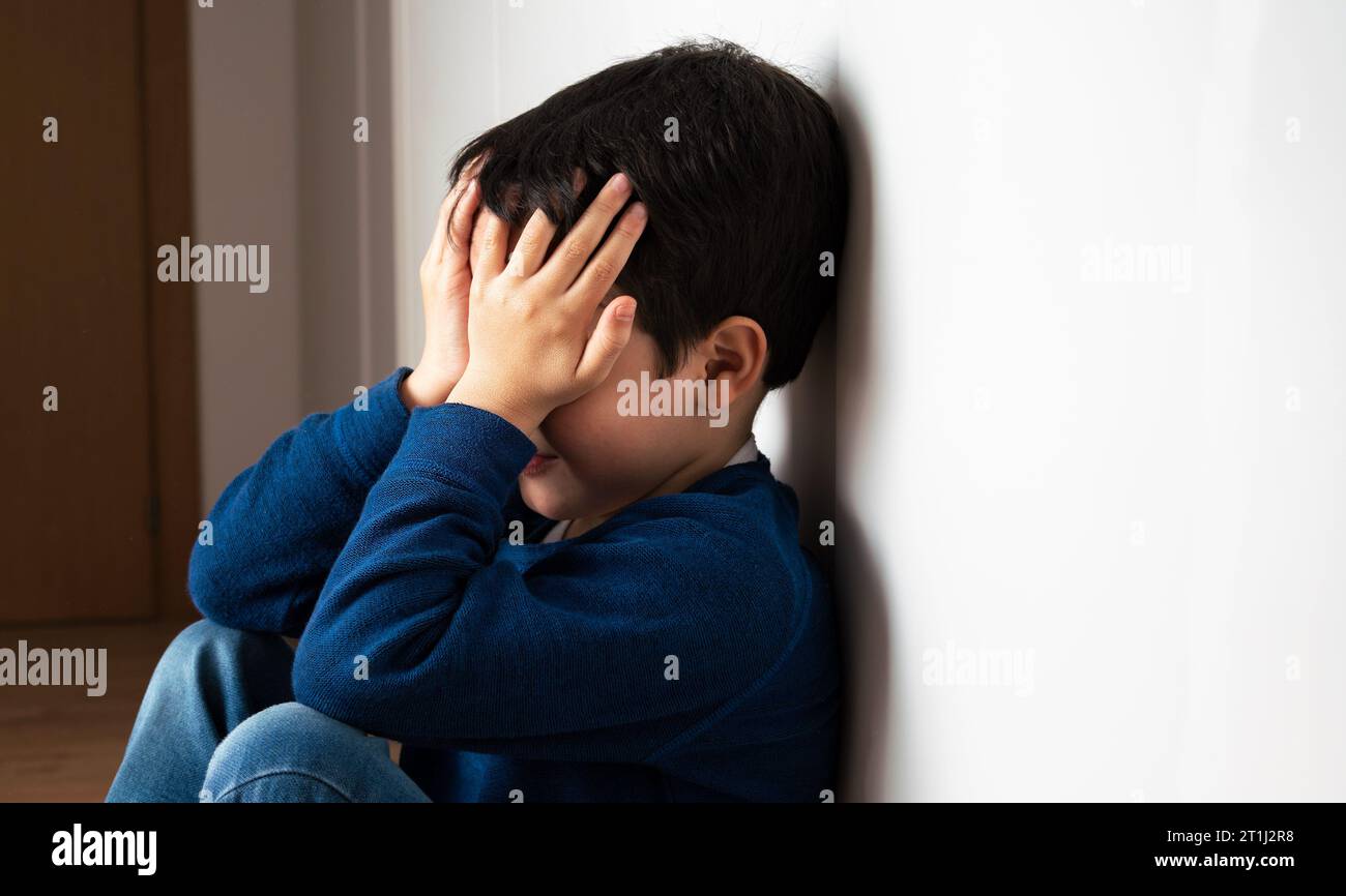 Upset boy with head in hands sitting on floor concept of bullying ...