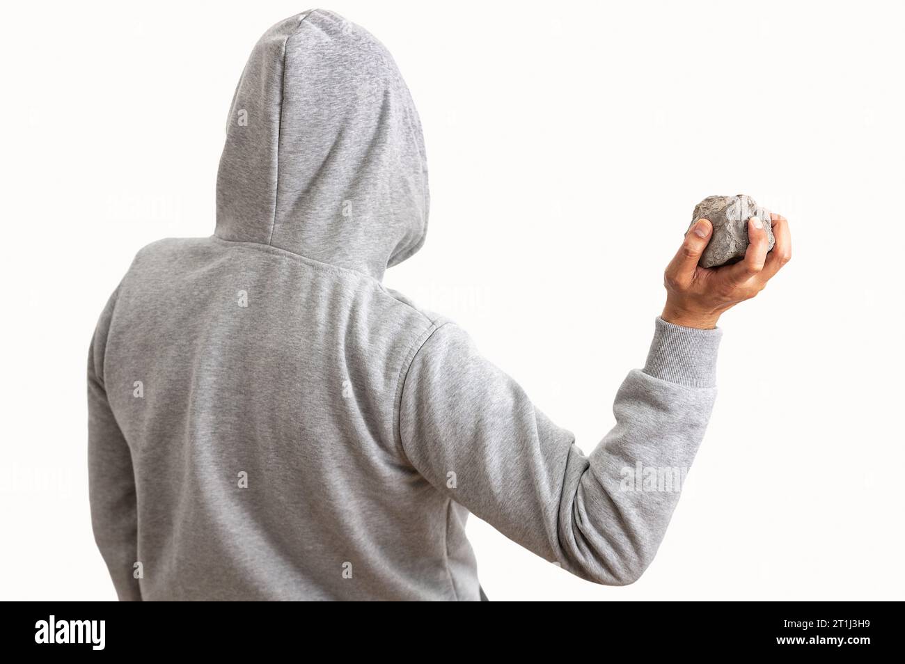Rear view of a man holding a stone to throw it with white background ...