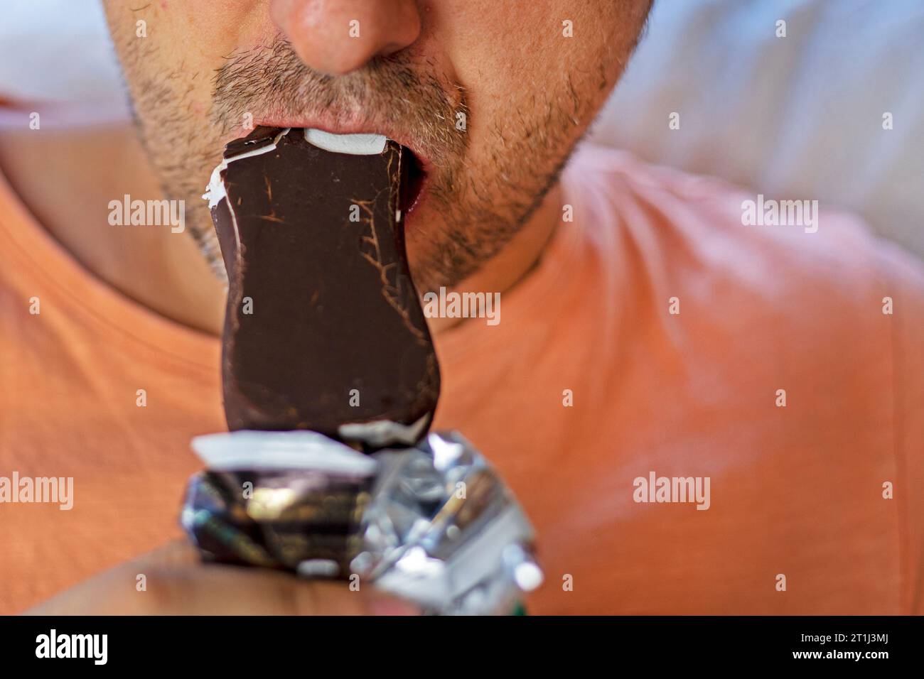 man eating chocolate ice cream biting pieces onto sticks Stock Photo ...