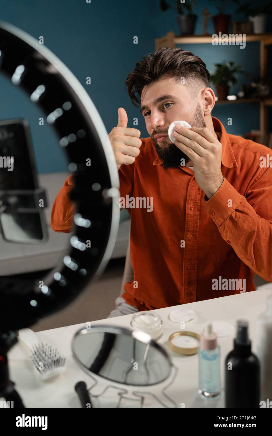 Applying toner. Handsome man blogger cleaning face with white pad ...