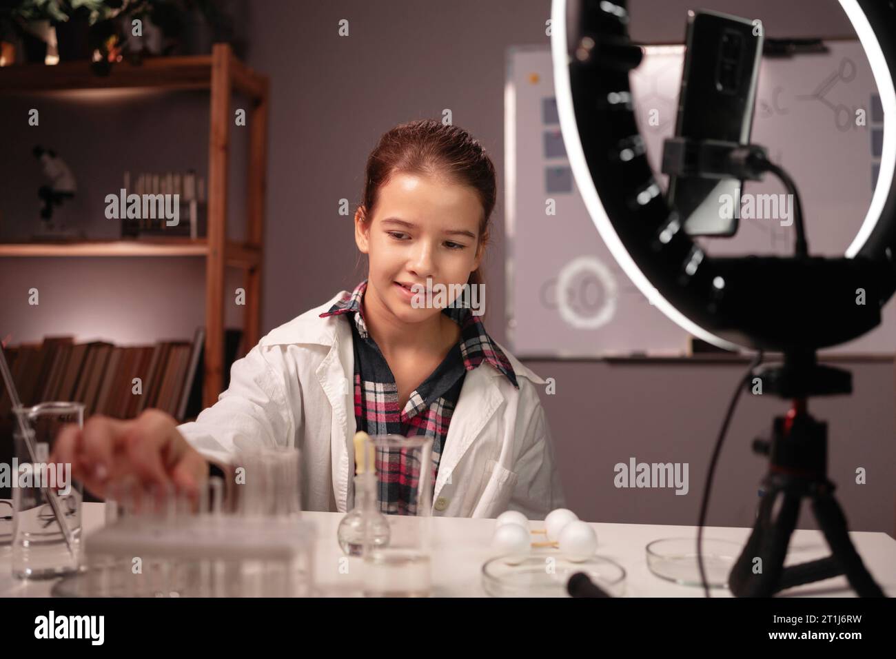 Schoolgirl in lab coat fond of filming video blogs making chemistry ...