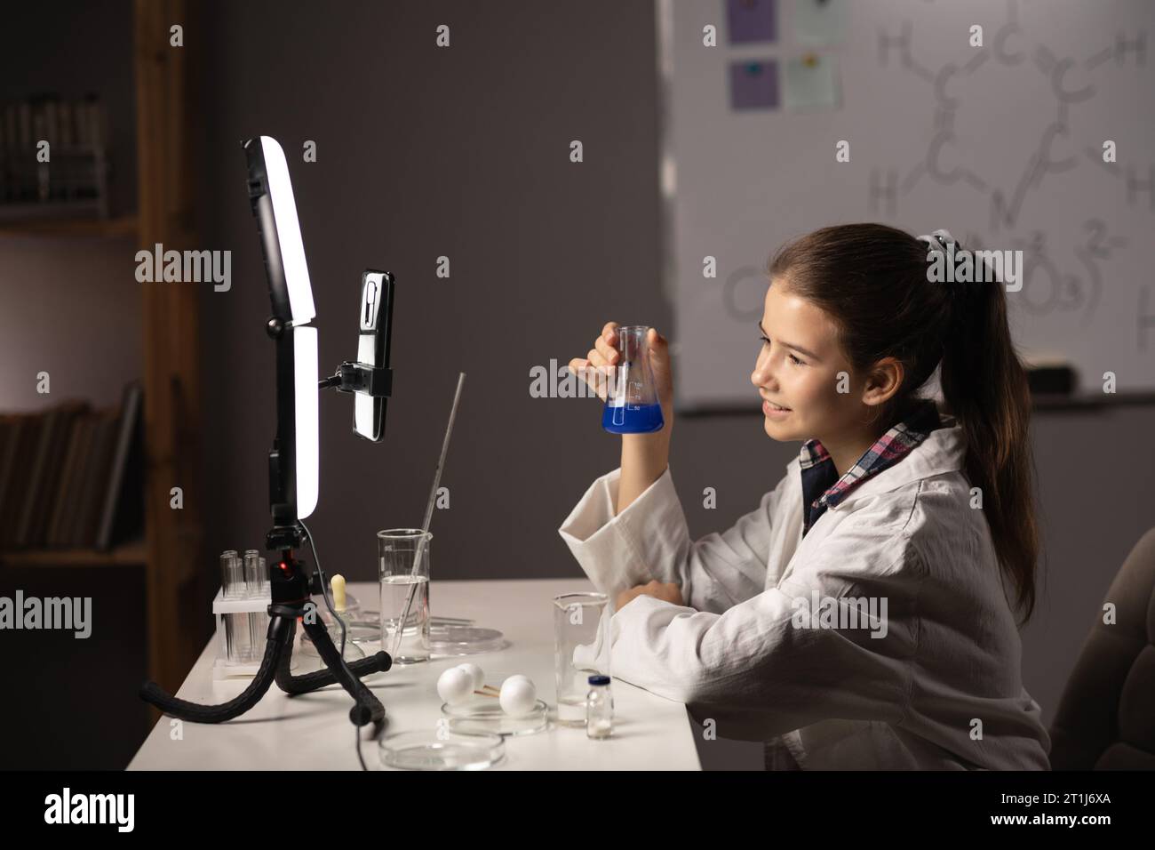 Smart girl showing a flask with the blue chemical to the camera while telling about the ...