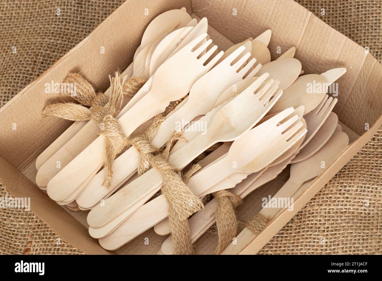 Wooden cutlery, tied with hessian jute fabric, in a cardboard tray on ...