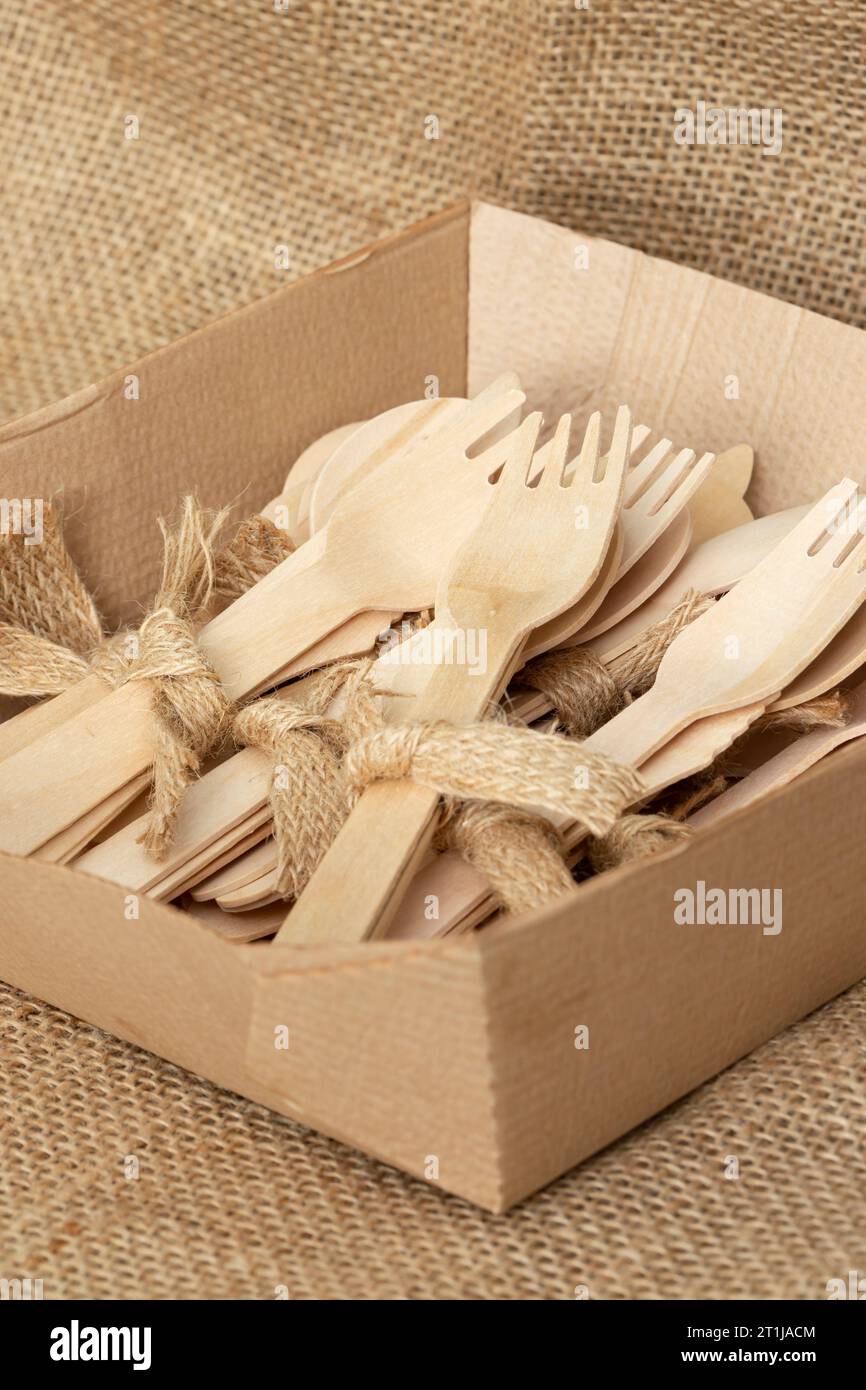 Wooden cutlery, tied with hessian jute fabric, in a cardboard tray on ...