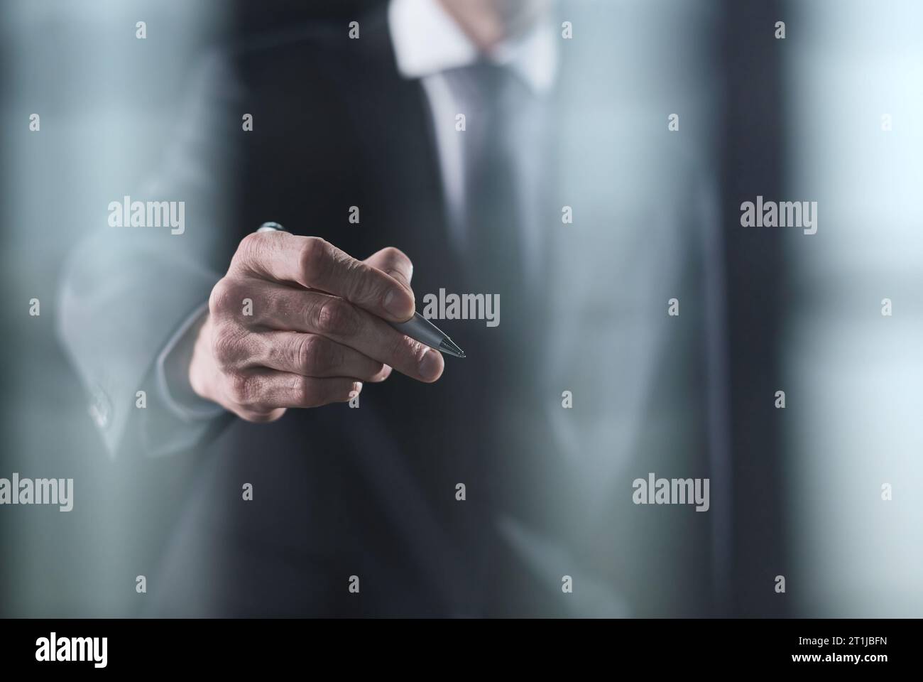 Left hand writing with marker on transparent board on black background ...