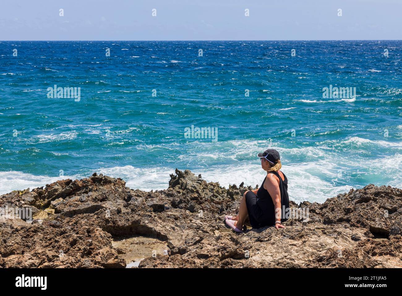 Beautiful view of rocky coast of Caribbean Sea and woman sitting on ...