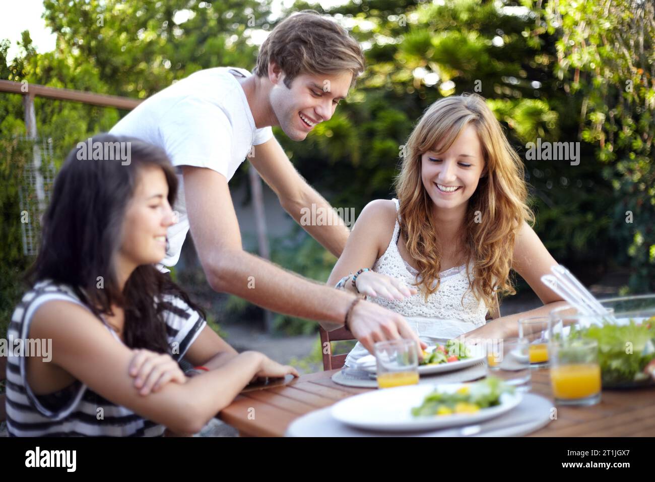 Happy, friends and food serve in backyard with salad at a table with ...