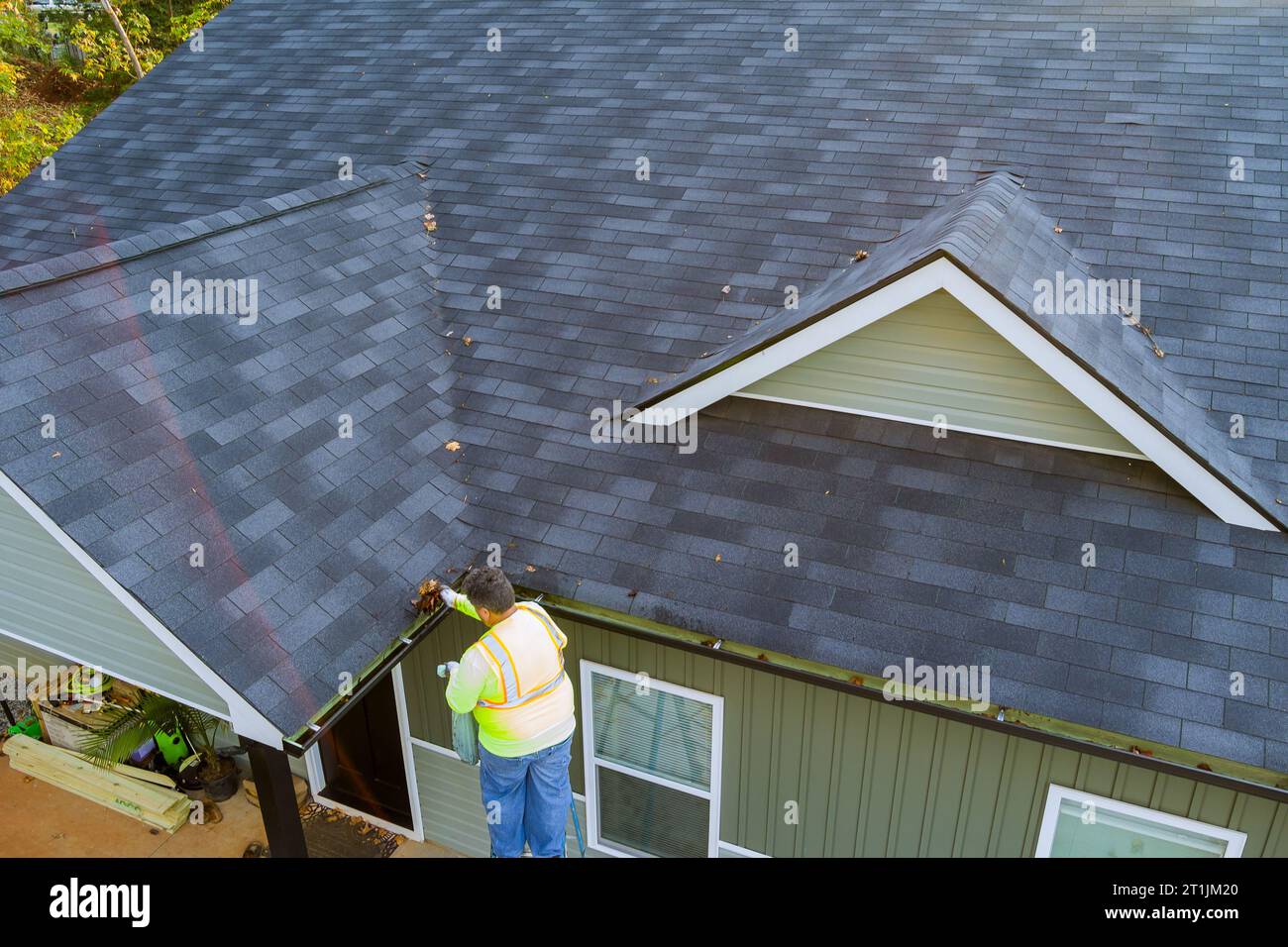 Worker cleans clogged roof gutter drain from dirt debris, as well as ...