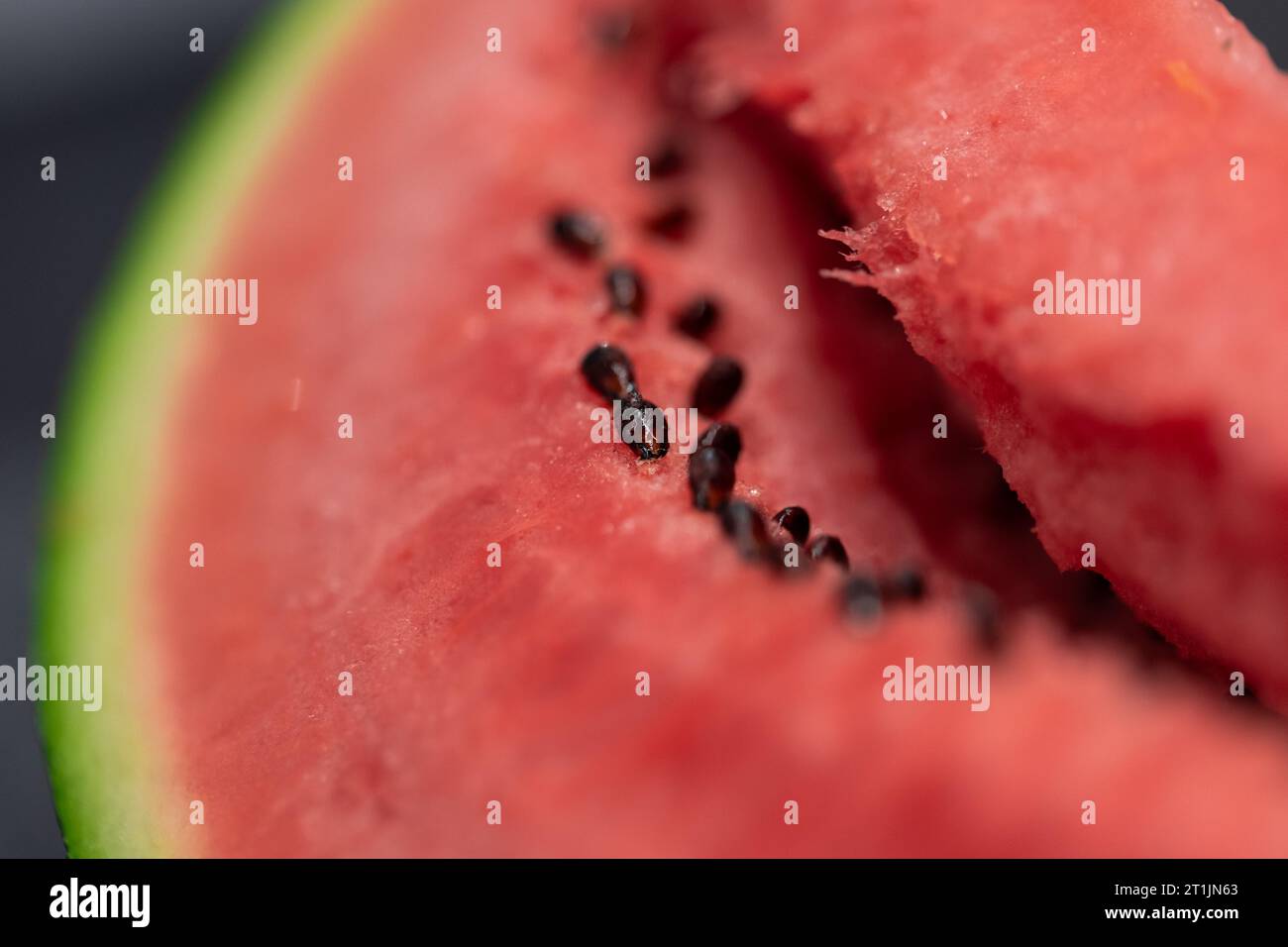 A closeup portrait of the black seeds sitting in the pink red pulp of a ...