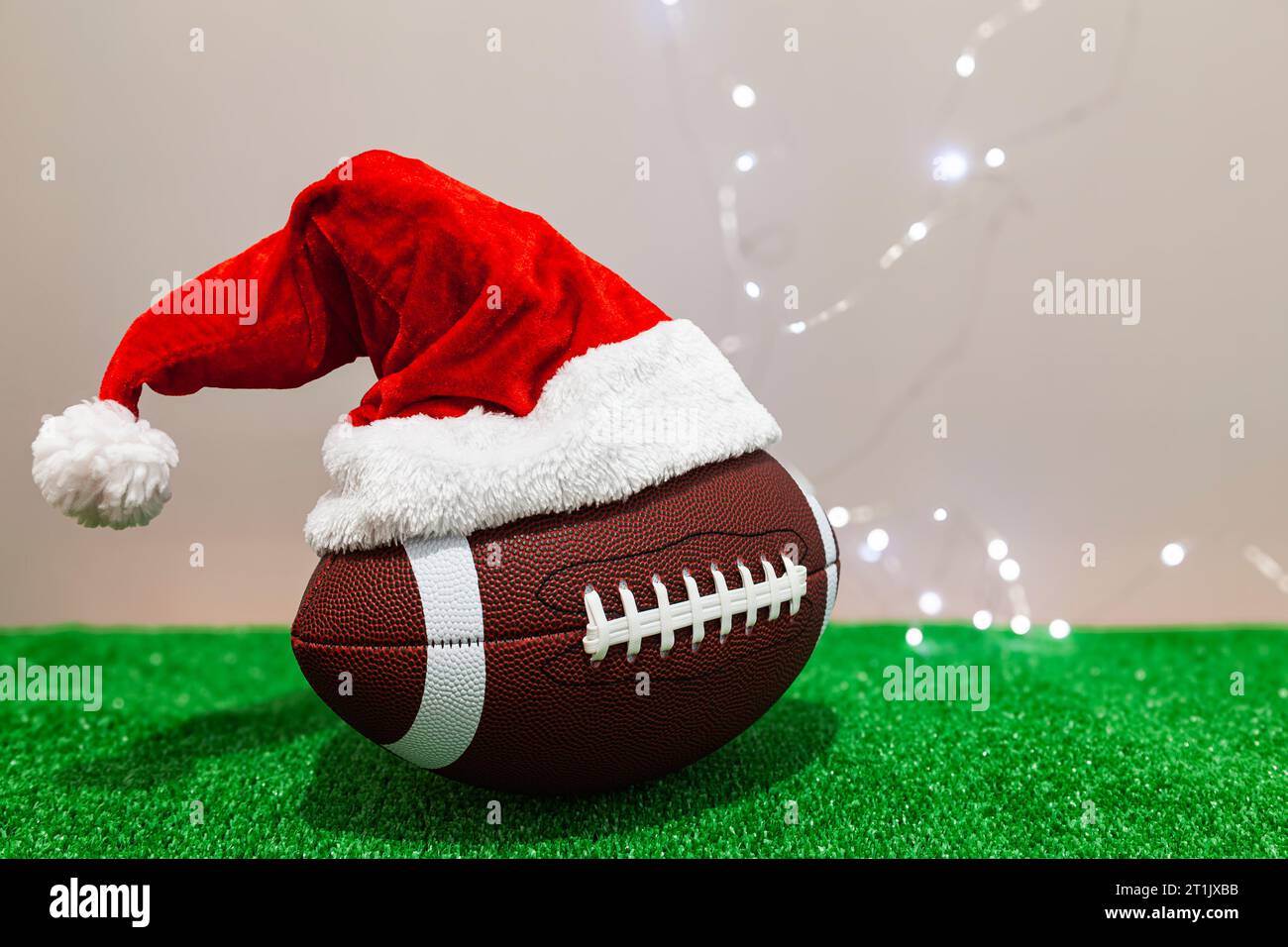American football ball wearing a Santa Claus hat over green grass in ...