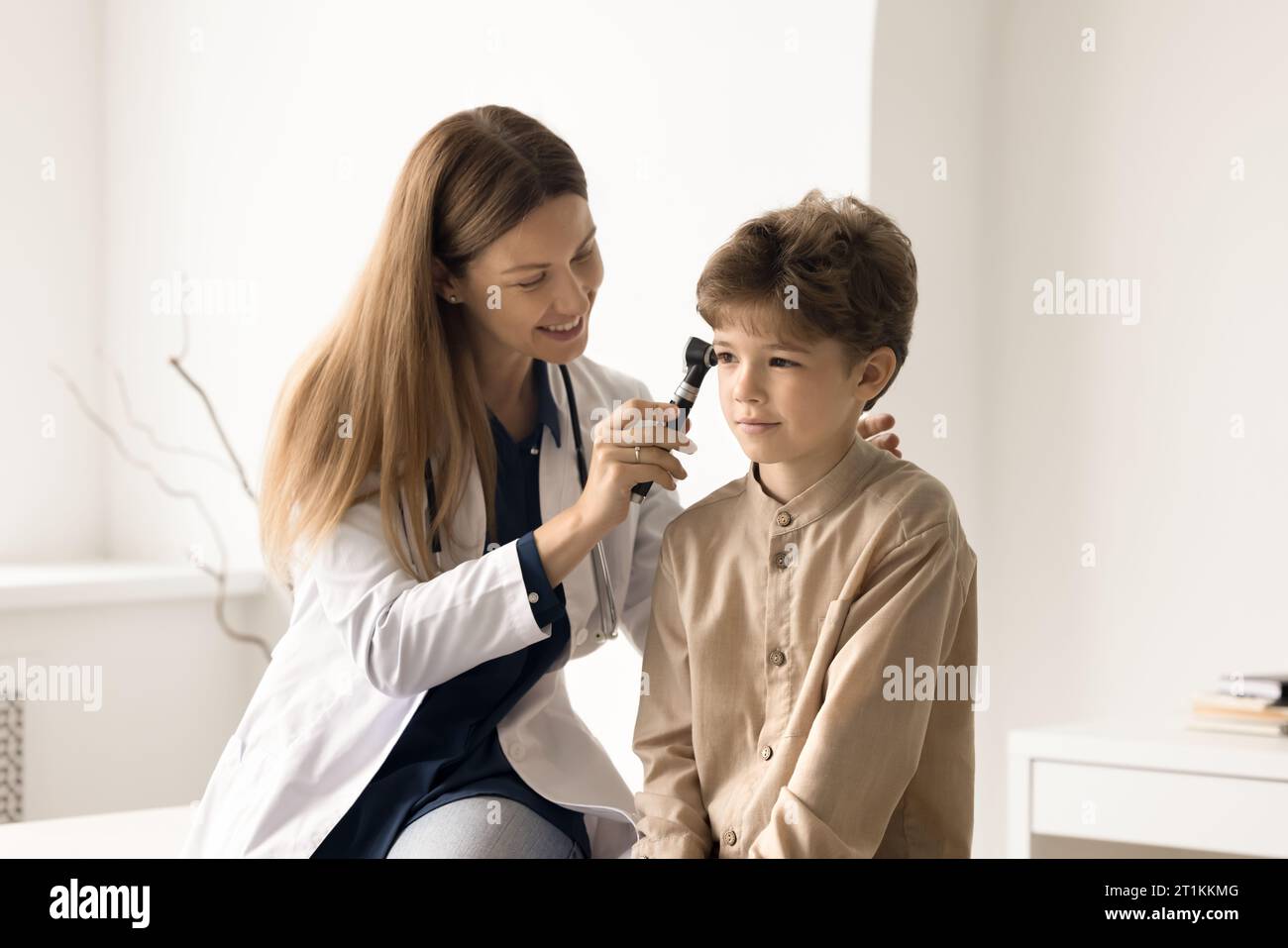 Female doctor examining boy ear with otoscope Stock Photo - Alamy