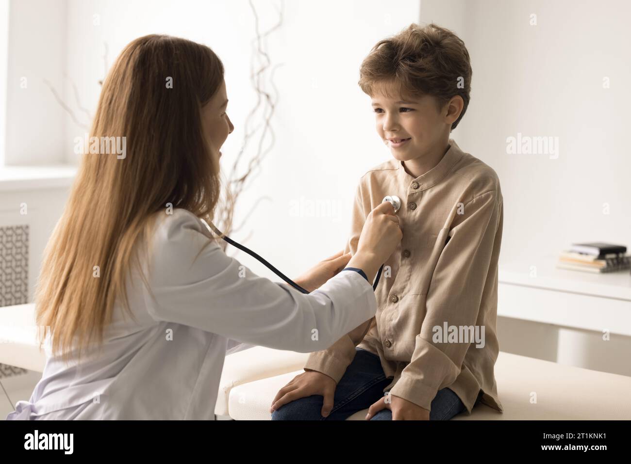Young female doctor examining little kid heartbeat with stethoscope ...