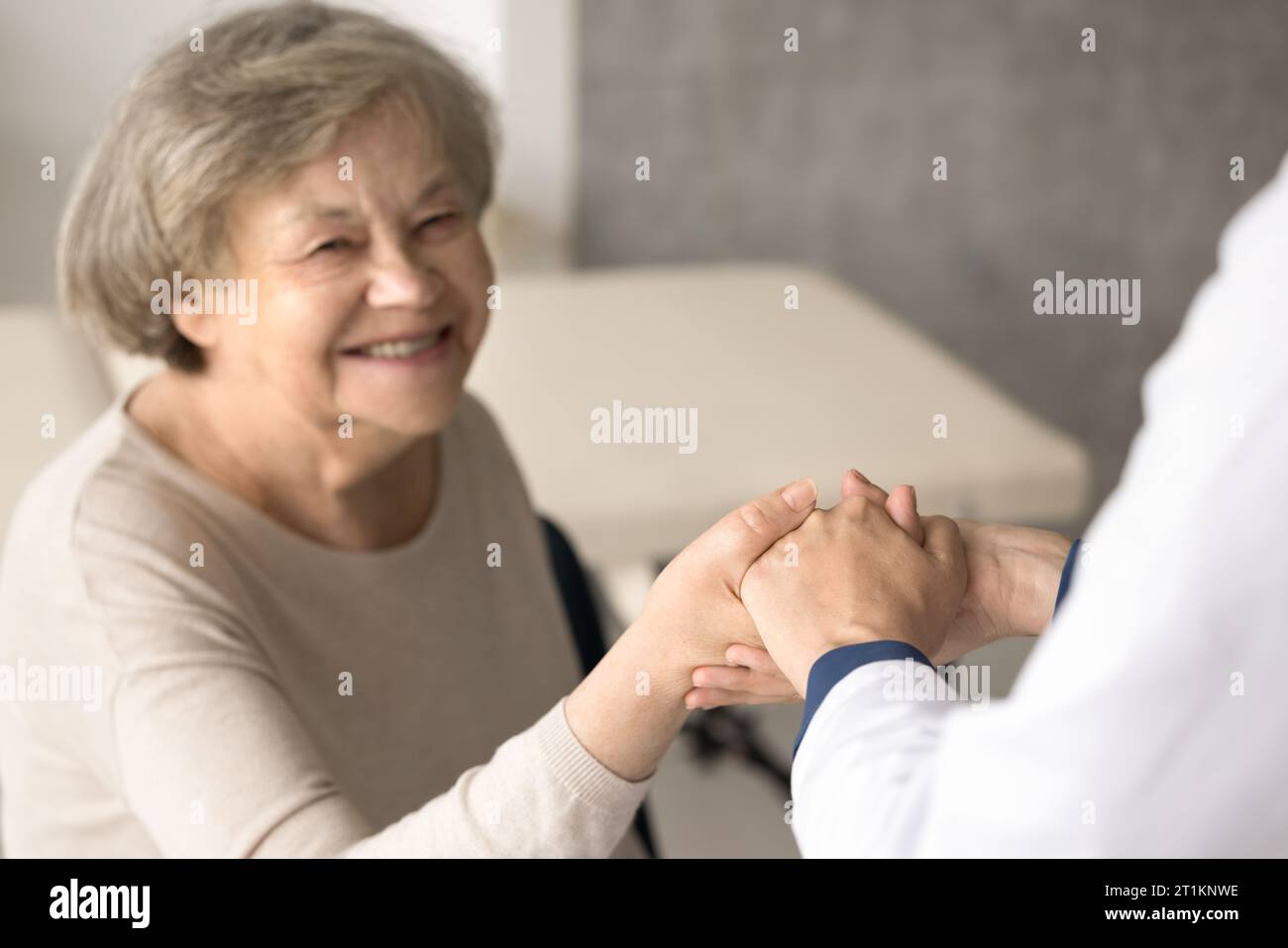 Young caring nurse hold hands of happy older pensioner patient Stock ...