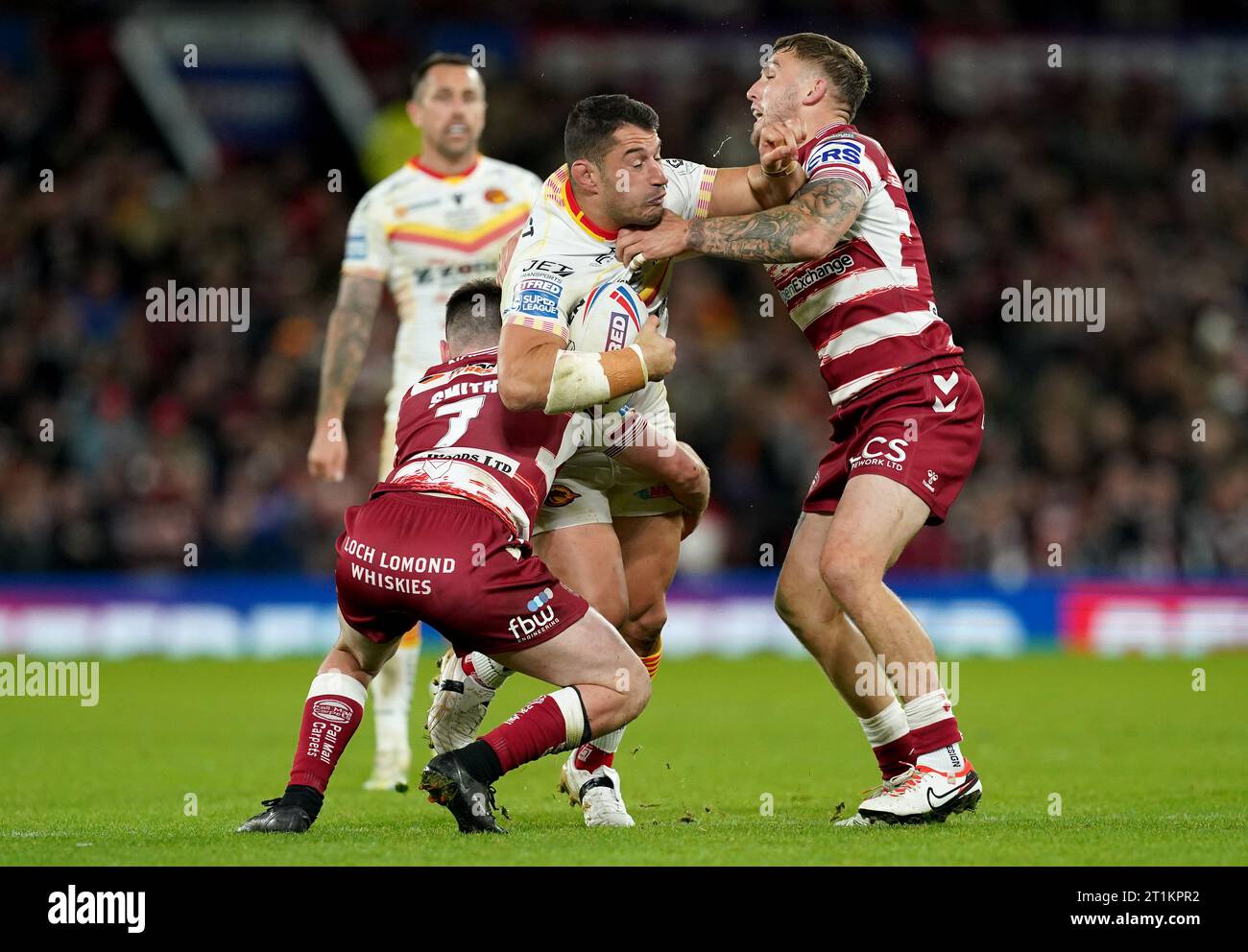 Catalans Dragons' Benjamin Garcia (centre) is tackled by Wigan Warriors ...