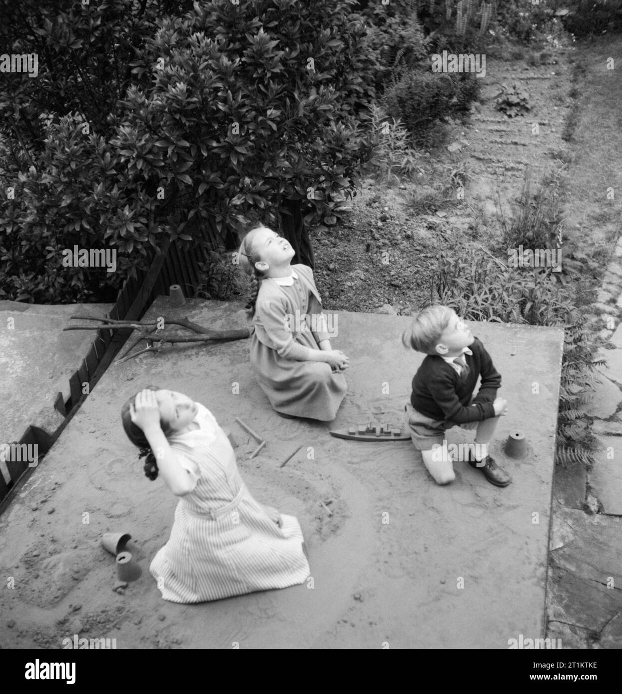 Three children watch aircraft pass over their garden in 1944. Three ...