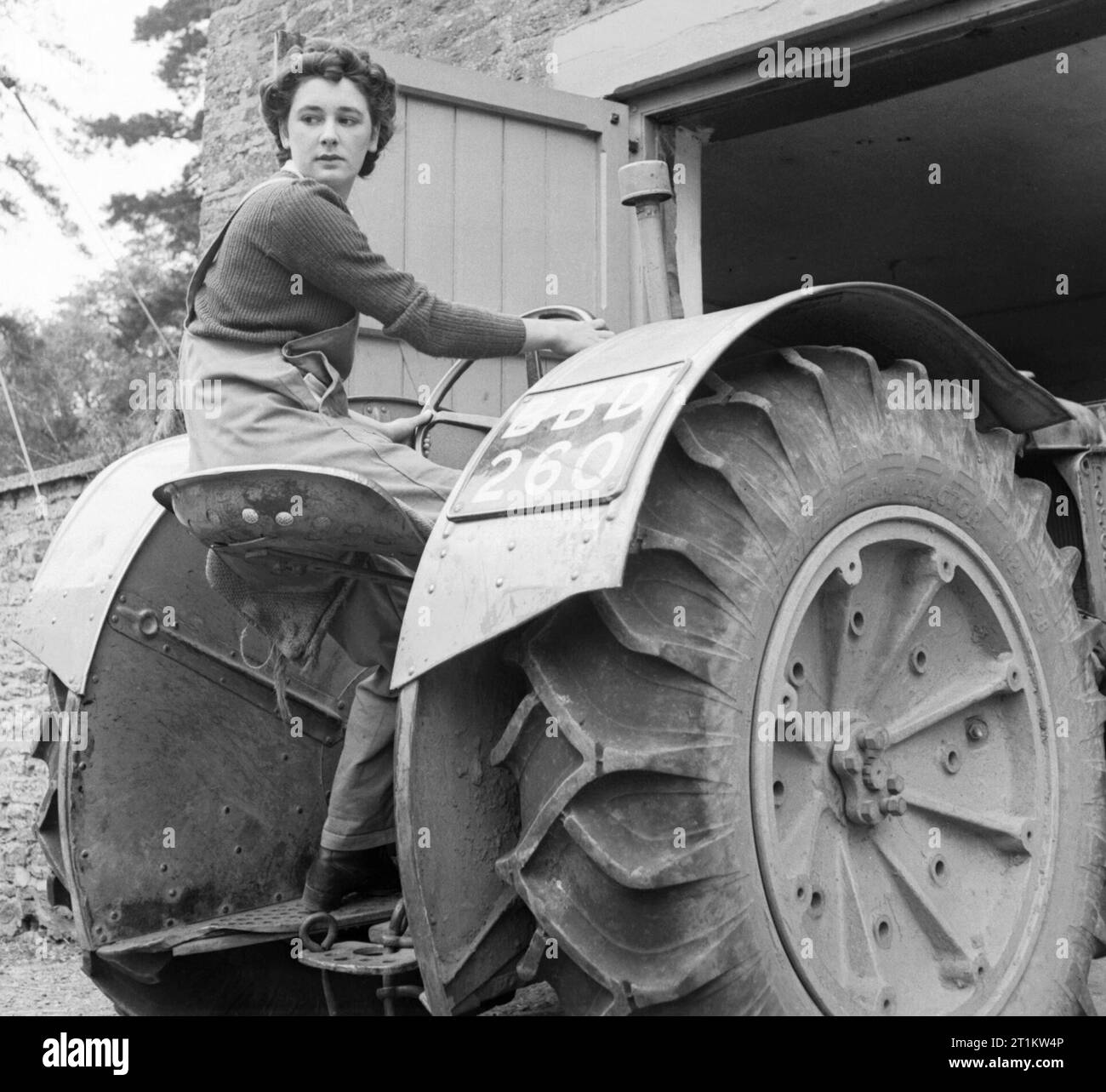 Anne Keys of the Women's Land Army reverses a tractor out of a shed ...