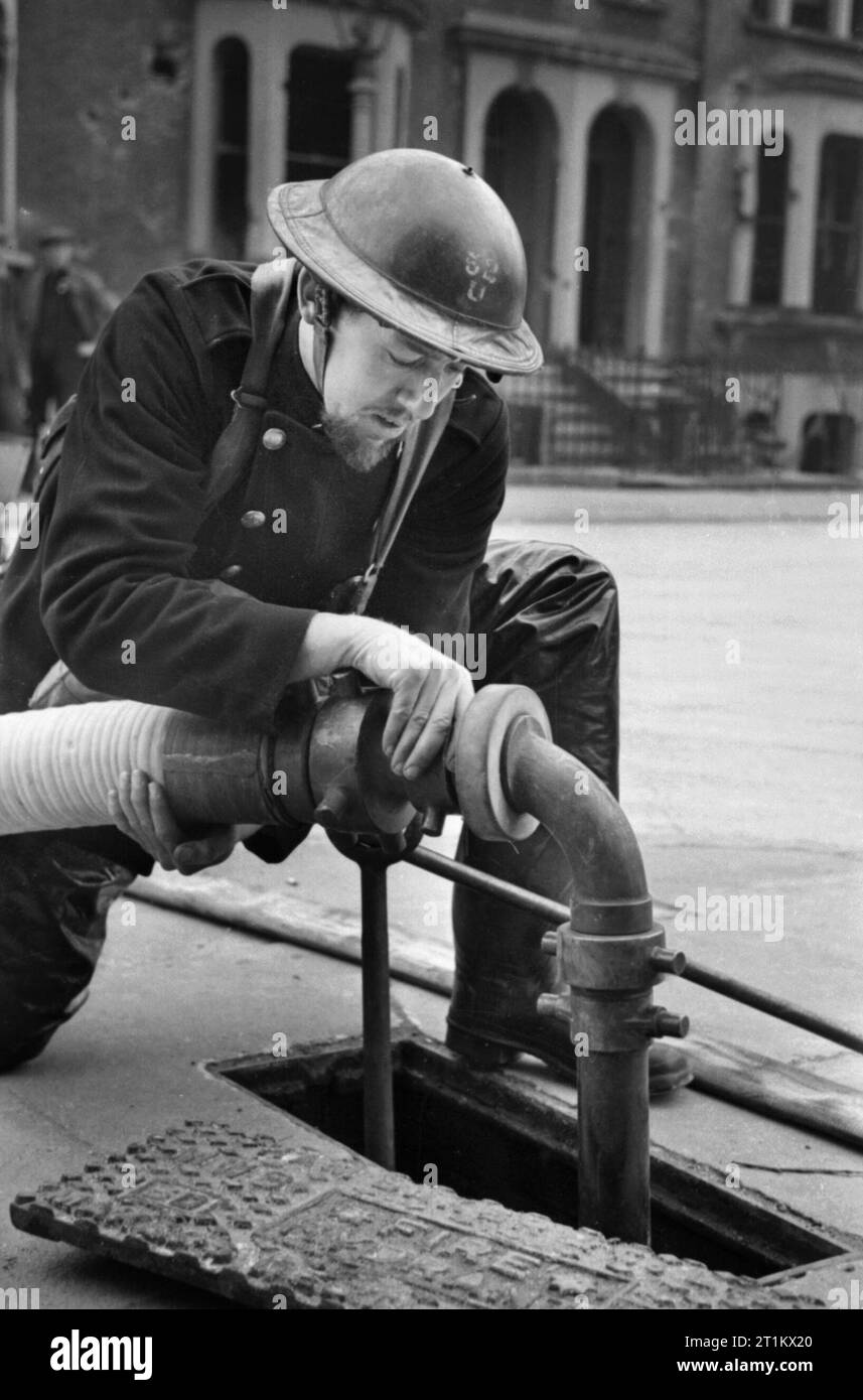 An Auxiliary Fireman attaching a hose to a fire hydrant in London ...