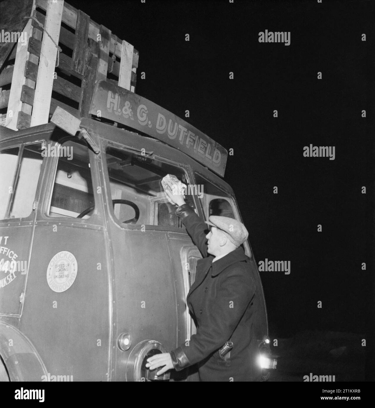A long-distance lorry driver cleaning the windscreen of his 7-ton ...