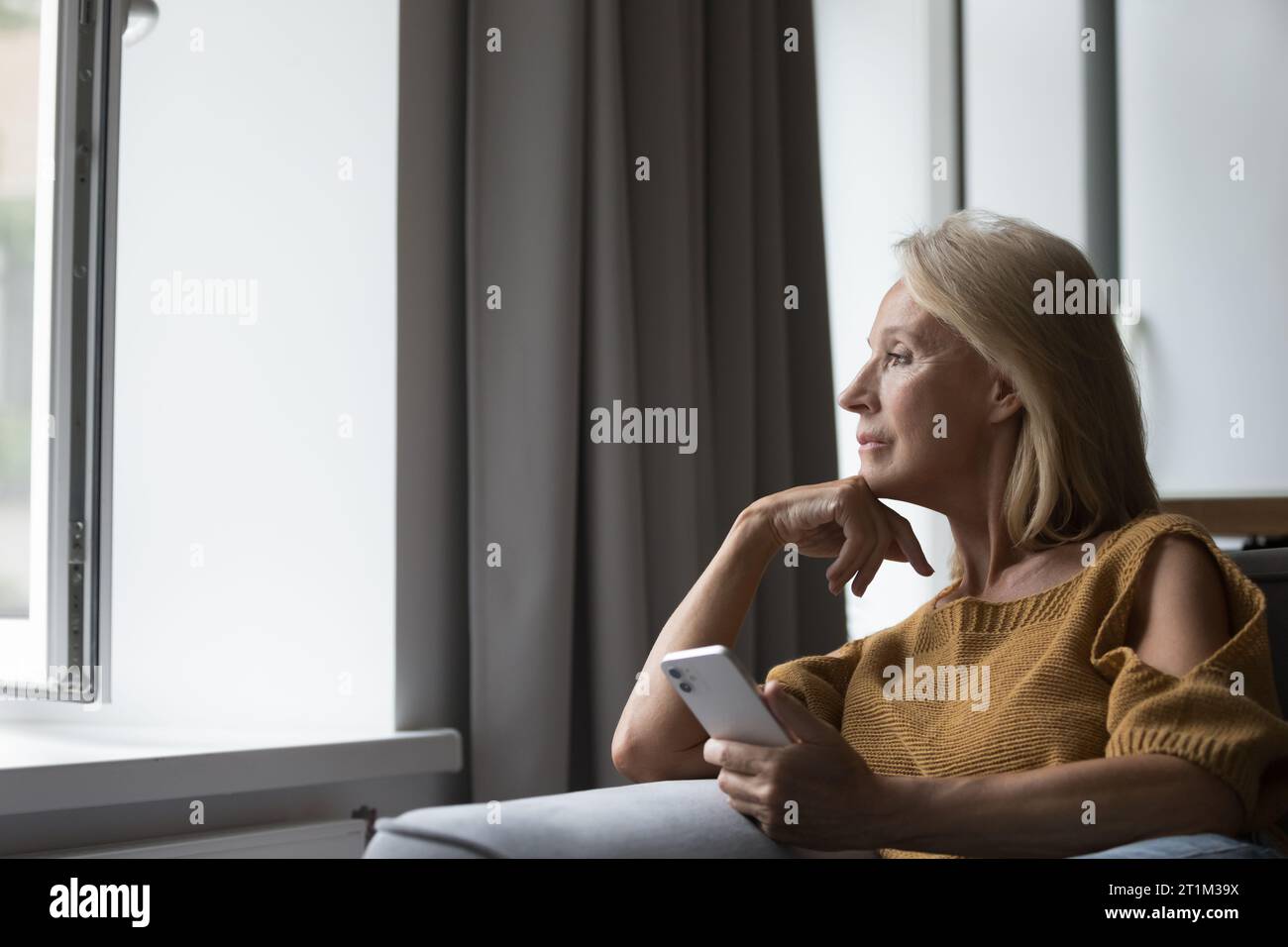 Thoughtful serious older woman holding smartphone, thinking over bad ...