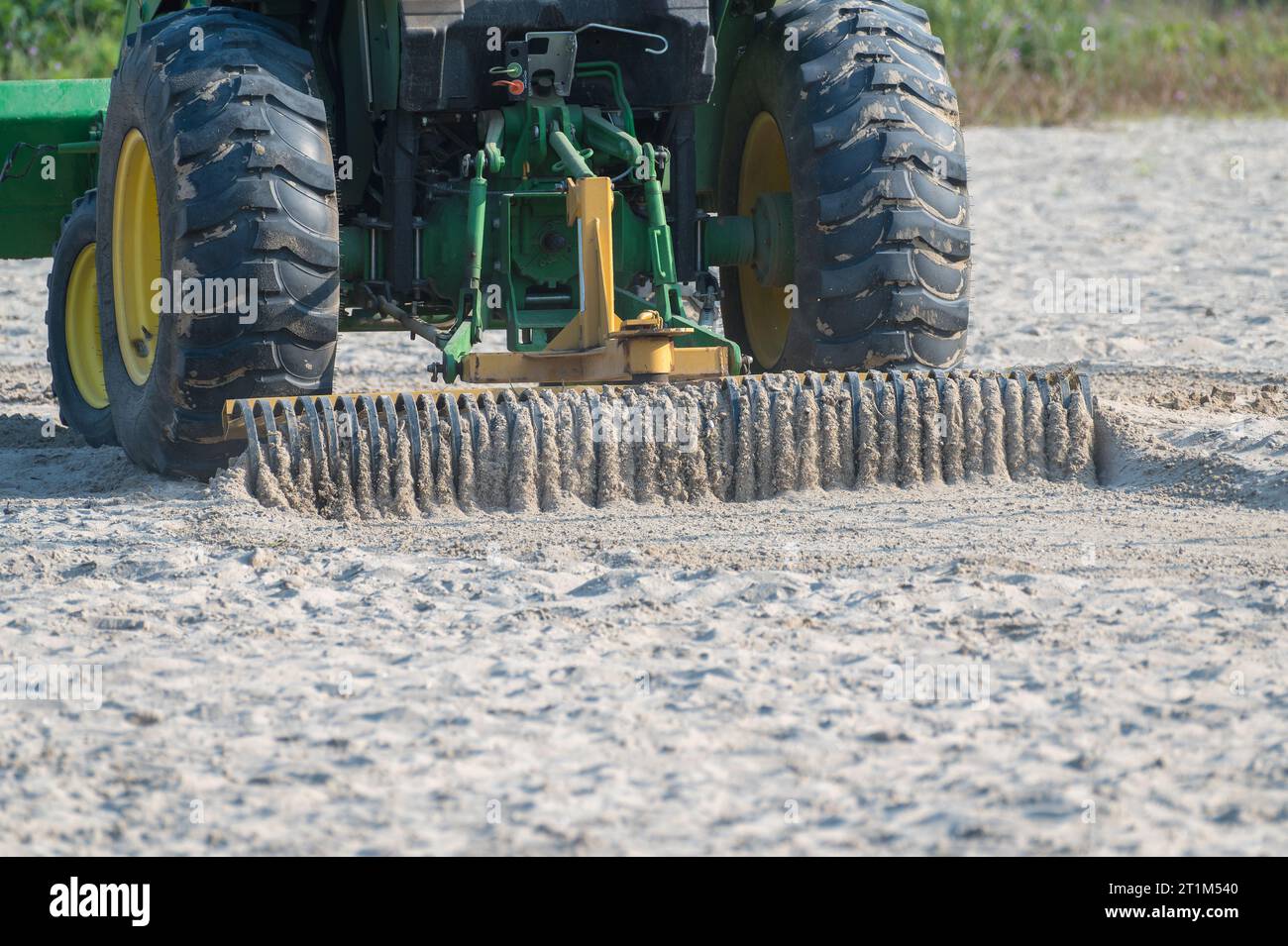 Tractor cleans sand by raking it and picking up debri on beach ...