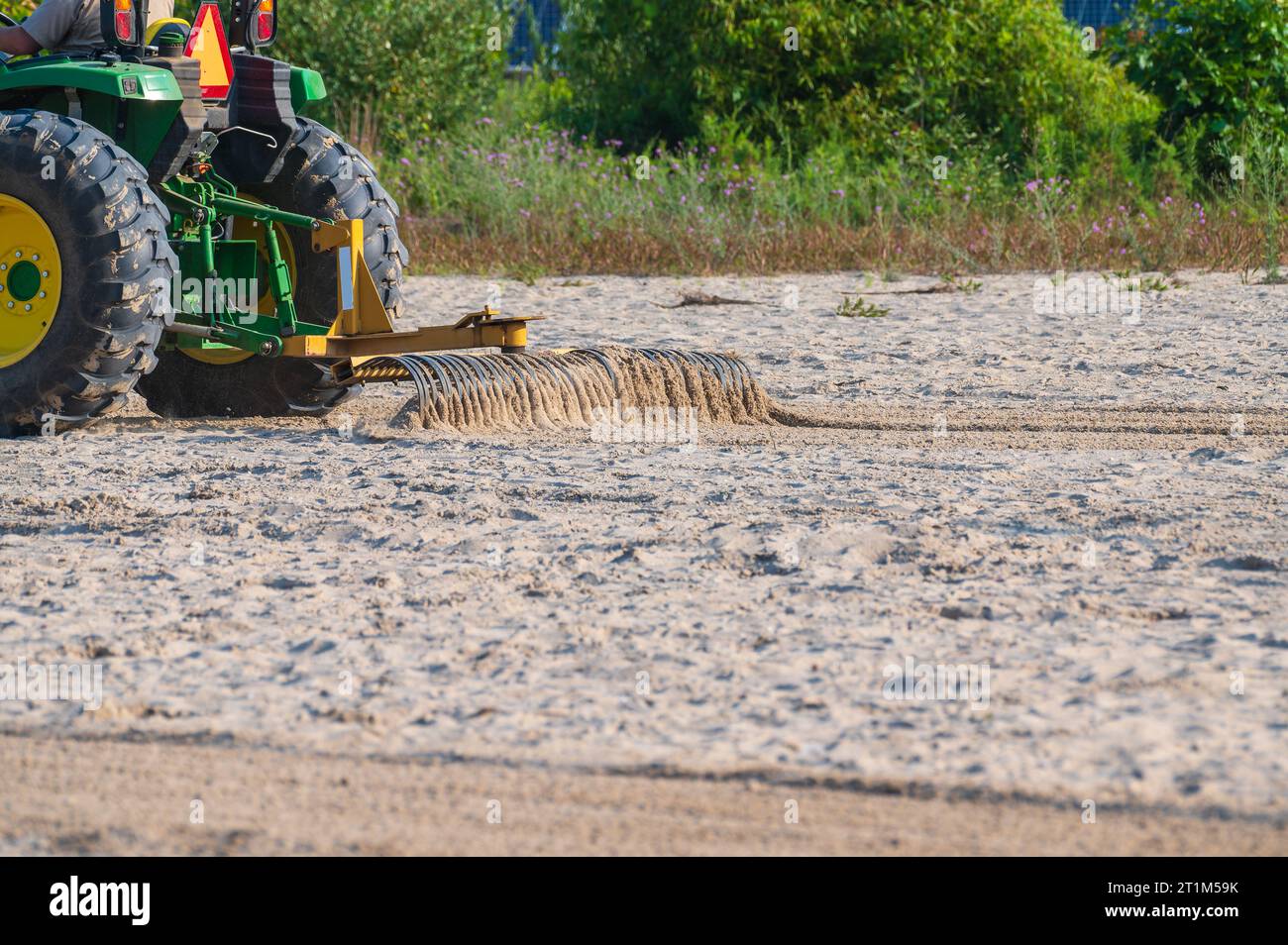 Tractor cleans sand by raking it and picking up debri on beach ...