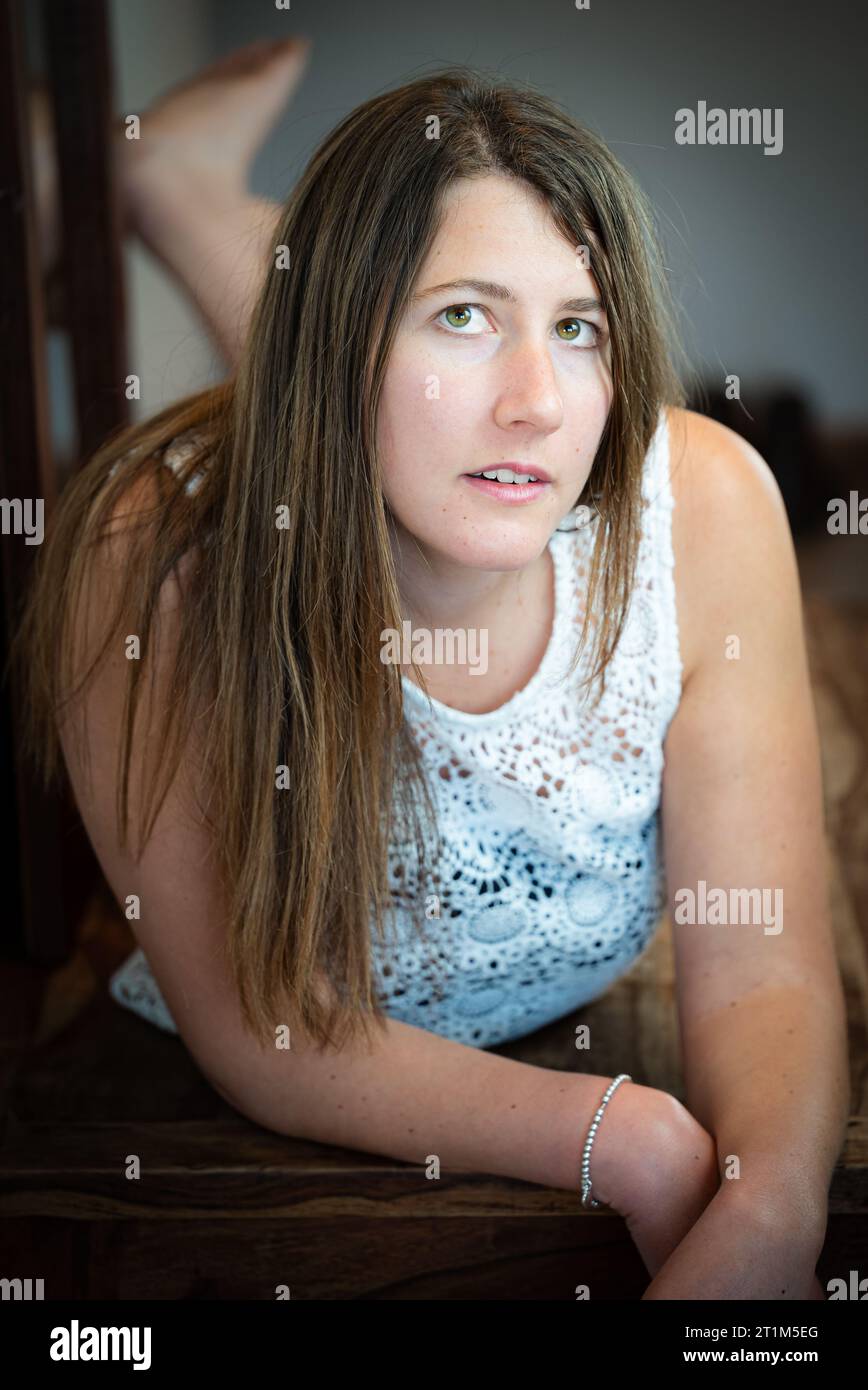 A cheerful young woman lying on a bed with one leg propped up Stock ...