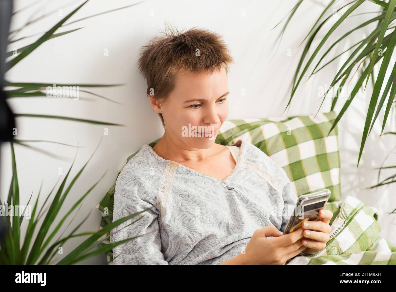 A middle-aged woman spends her entire day in bed, staring at her phone ...