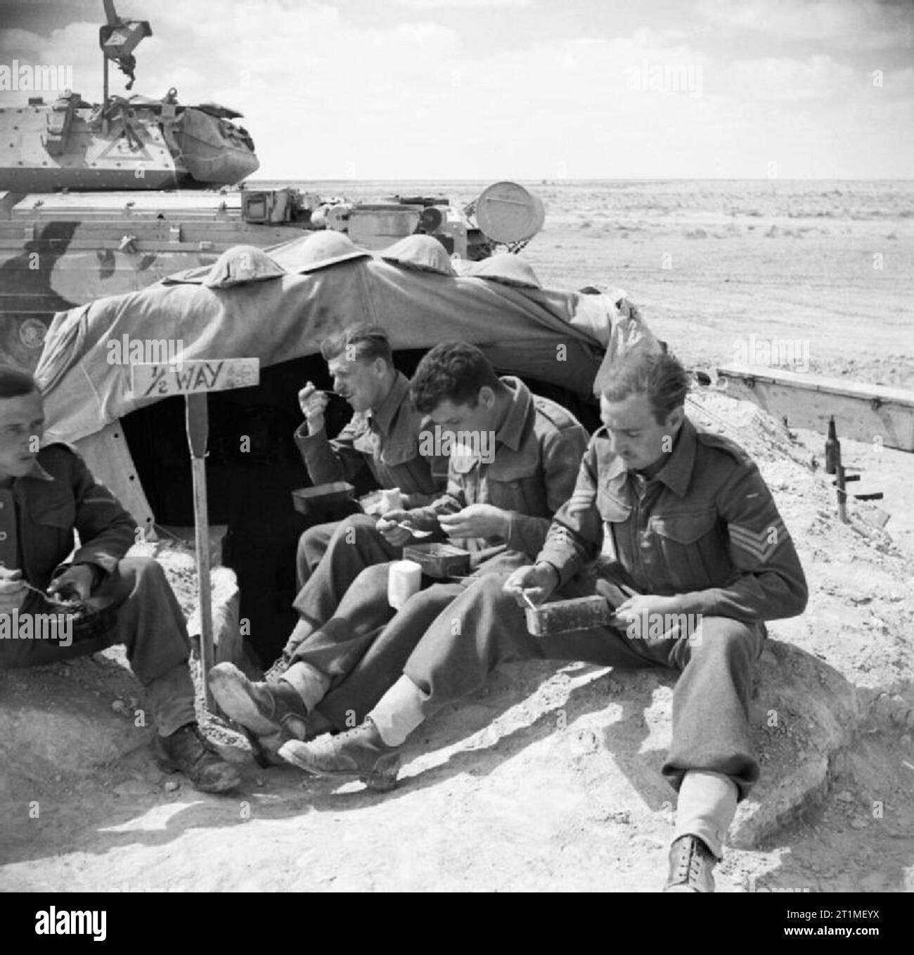 The crew of a Crusader tank eat their breakfast beside their vehicle ...