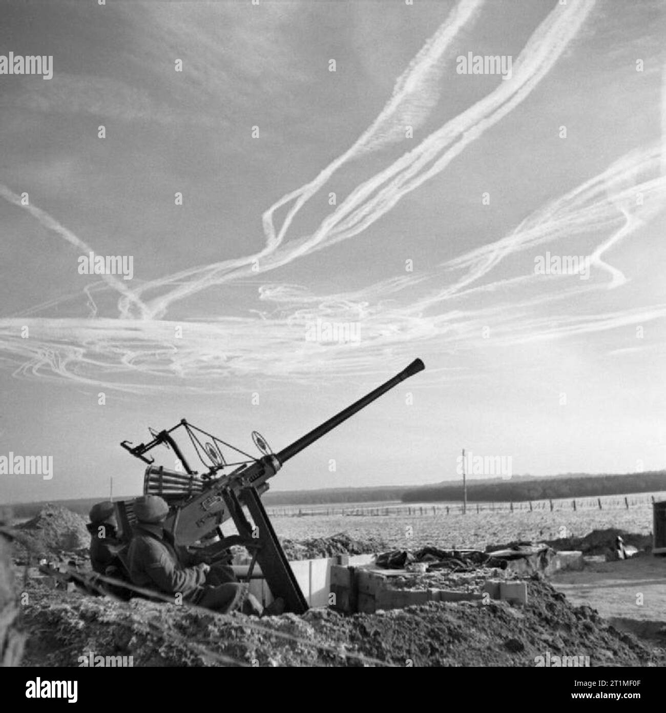 The crew of a Bofors anti-aircraft gun view vapour trails in the sky ...
