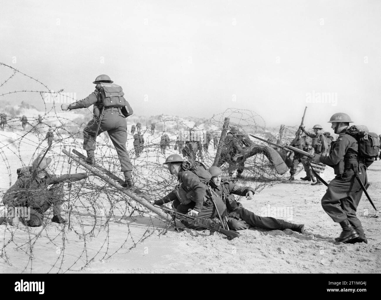 Troops of the 7th Battalion, the Suffolk Regiment, negotiate barbed ...