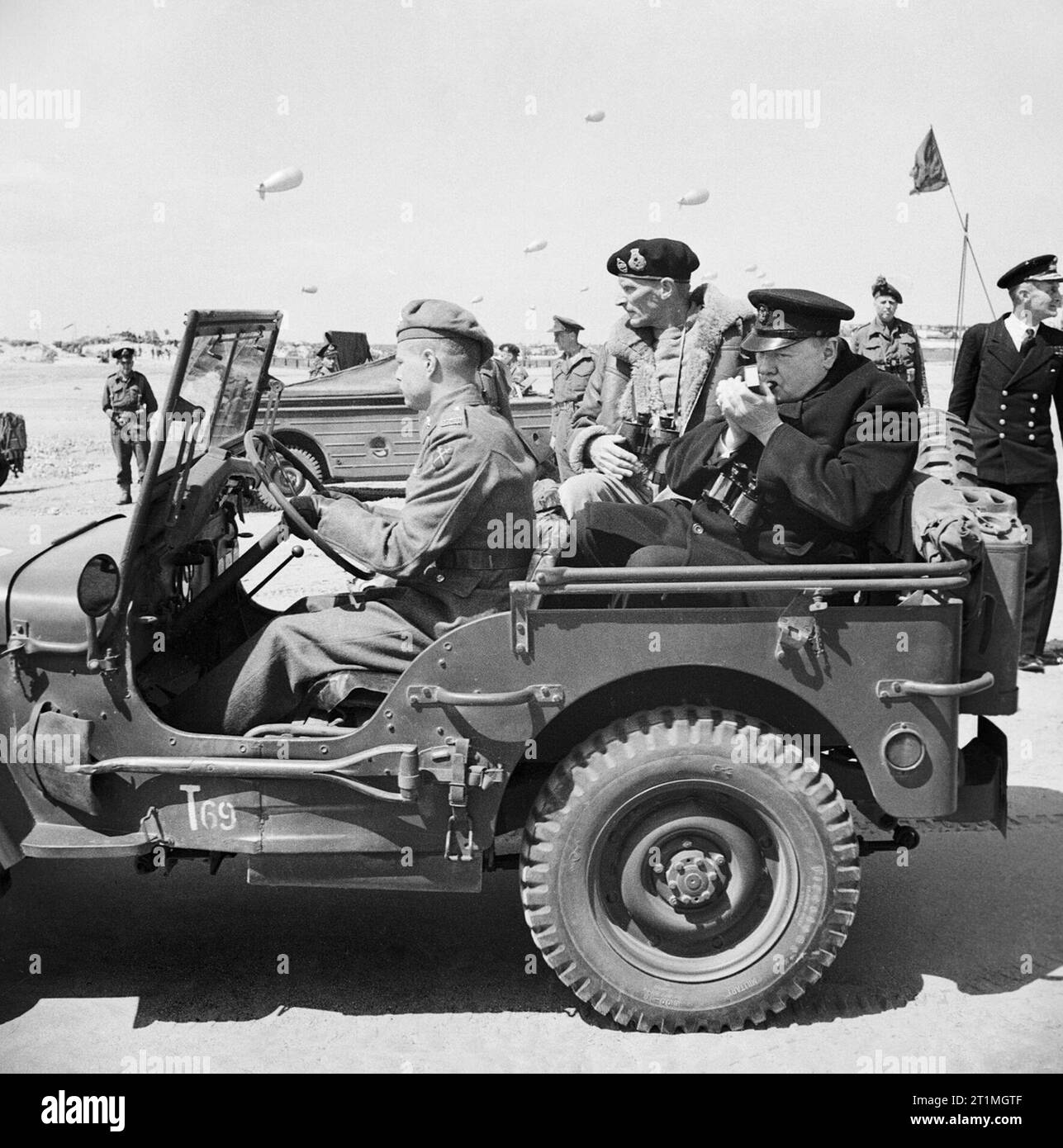 Winston Churchill lights a cigar in the back of a jeep while touring ...