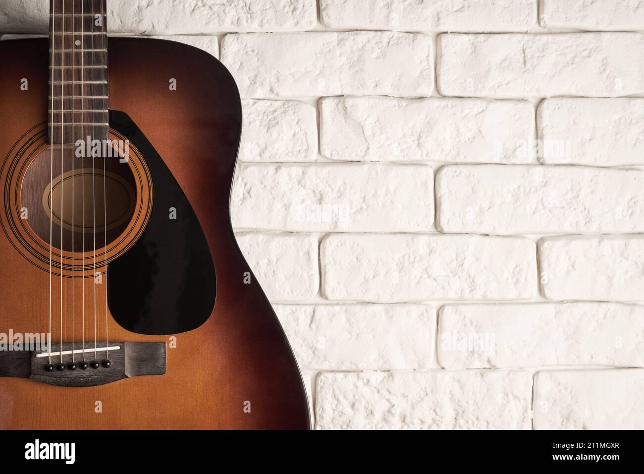 Traditional acoustic guitar in the interior next to the white brick ...