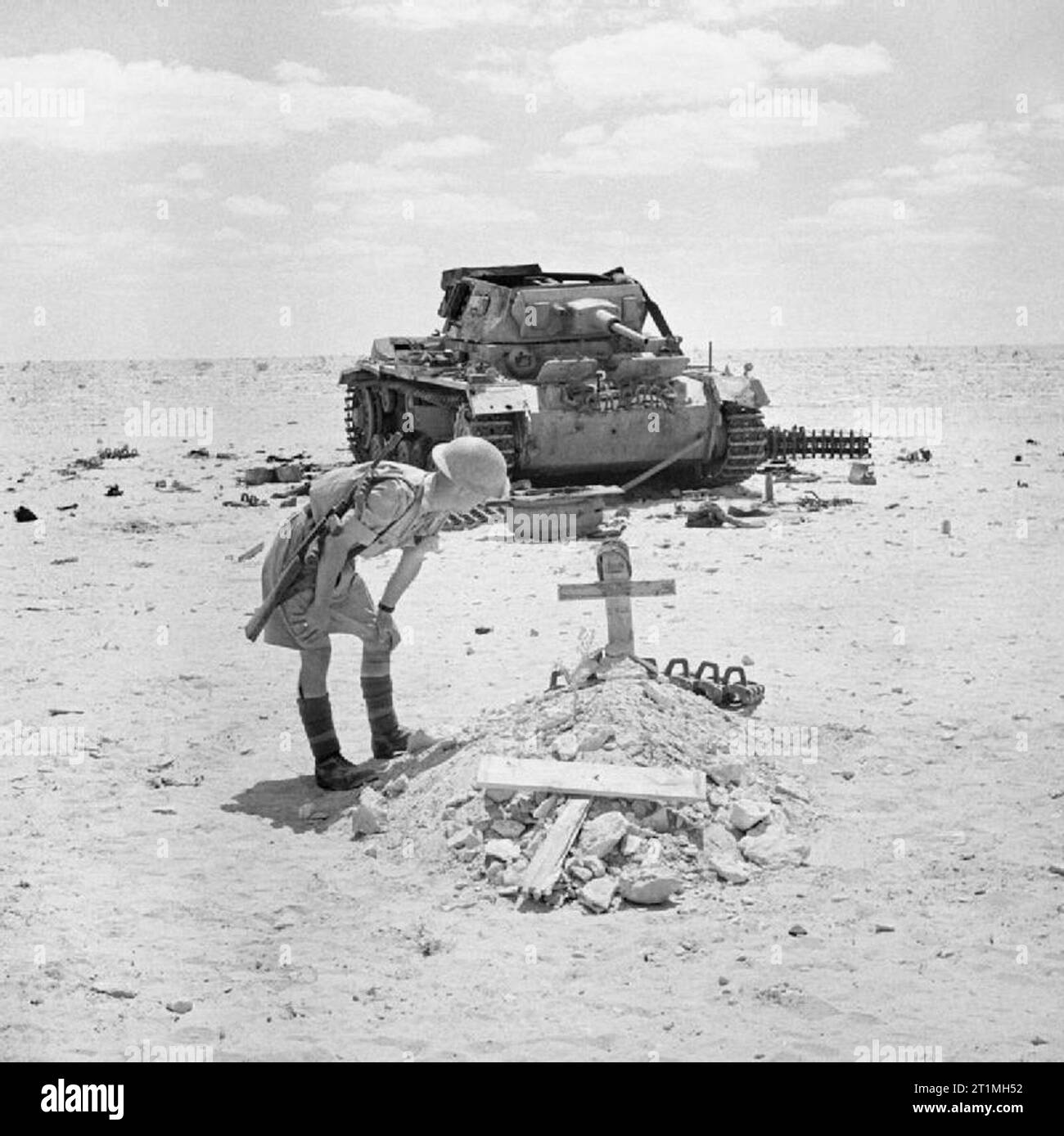 A British soldier inspects the grave of a German tank crewman, killed ...