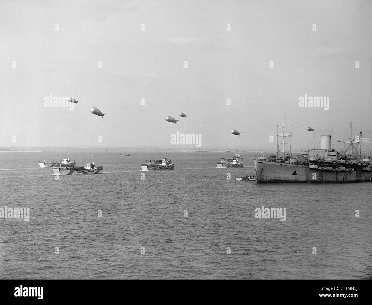 The Royal Navy during the Second World War Under a cover of barrage balloons, landing craft ...
