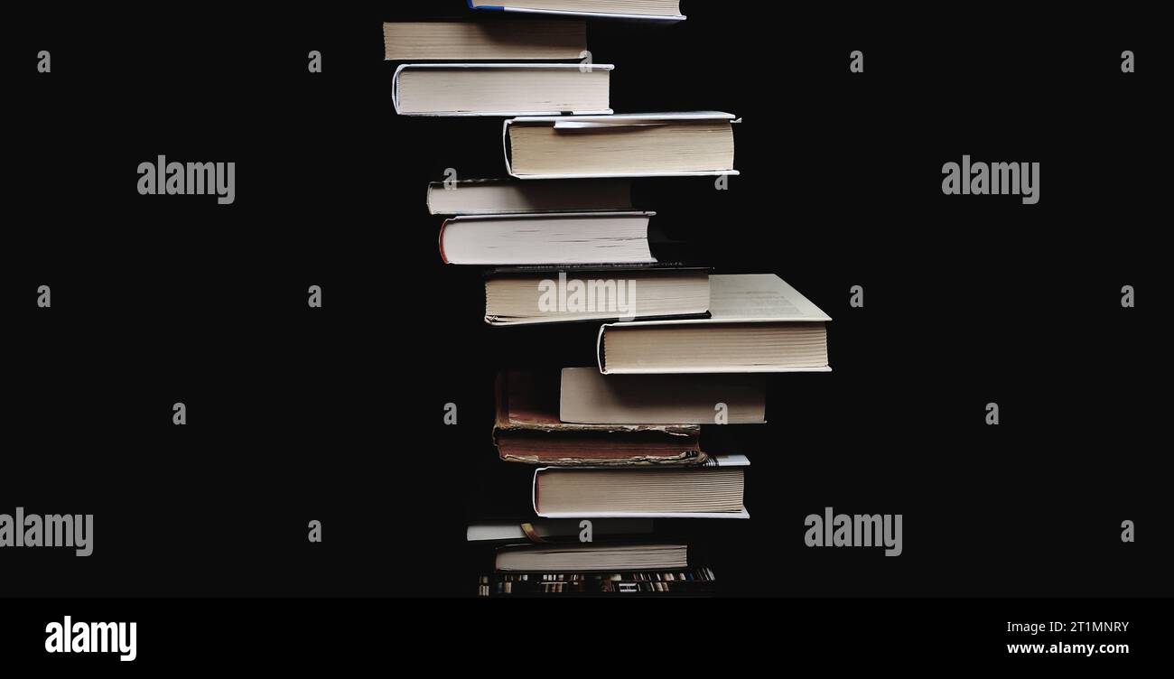 Composition of piled up books on a black background. Minimal central ...