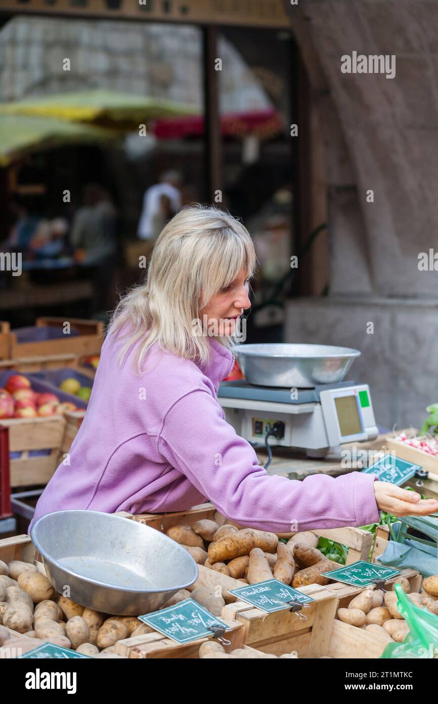 A French female stallholder at a vegetable stall prepares to take ...