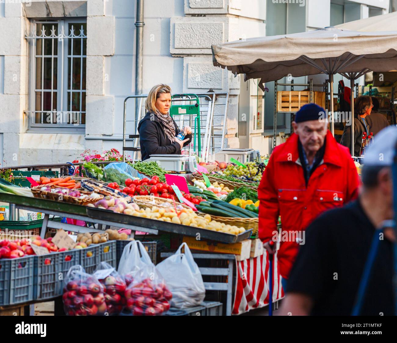 A local French female stallholder tends her fresh vegetables, fruit and ...