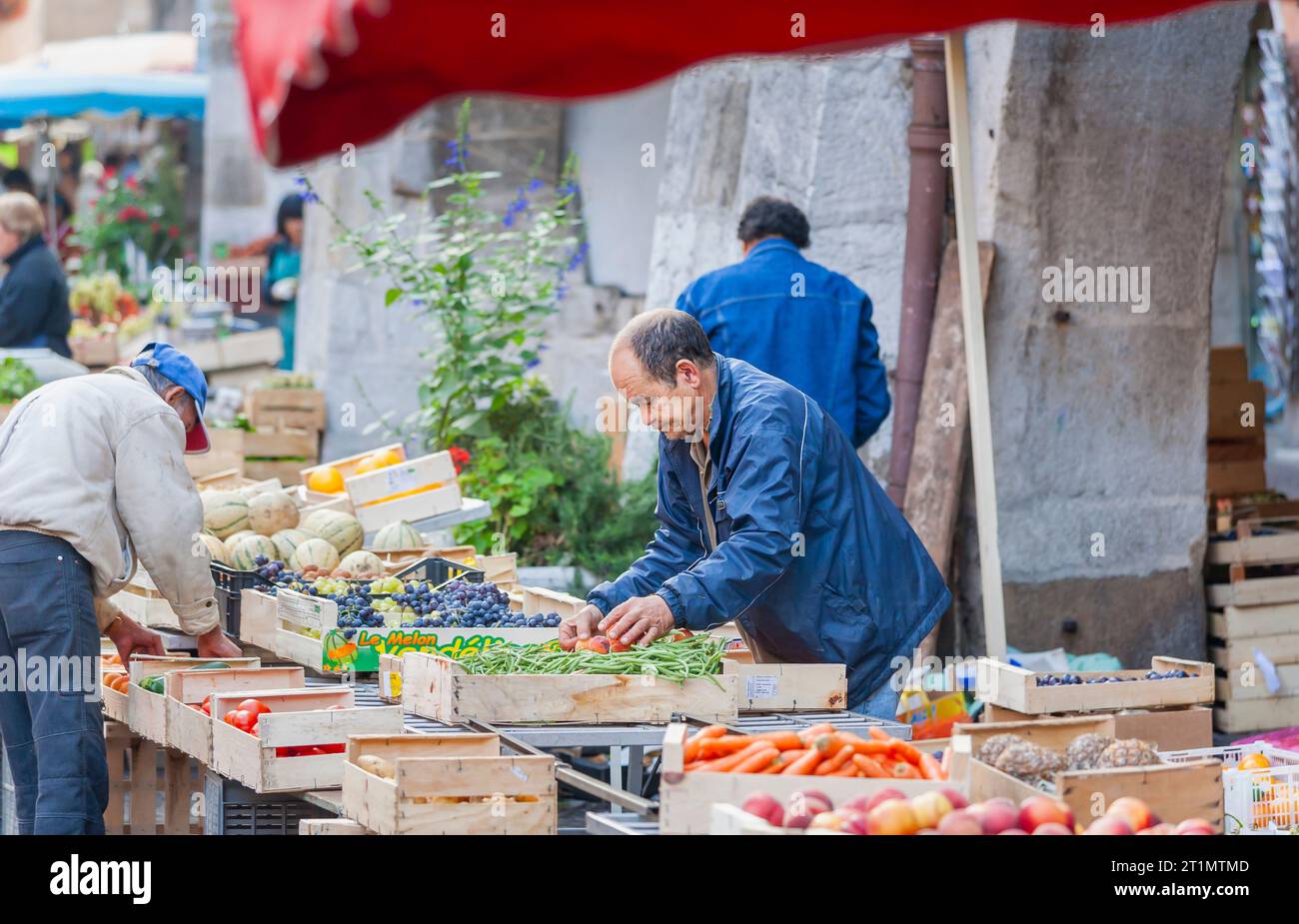 A local French male stallholder arranges his fresh fruit, vegetables ...