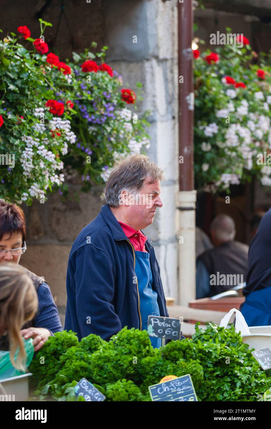 A local French male stallholder tends his fresh vegetables and produce ...