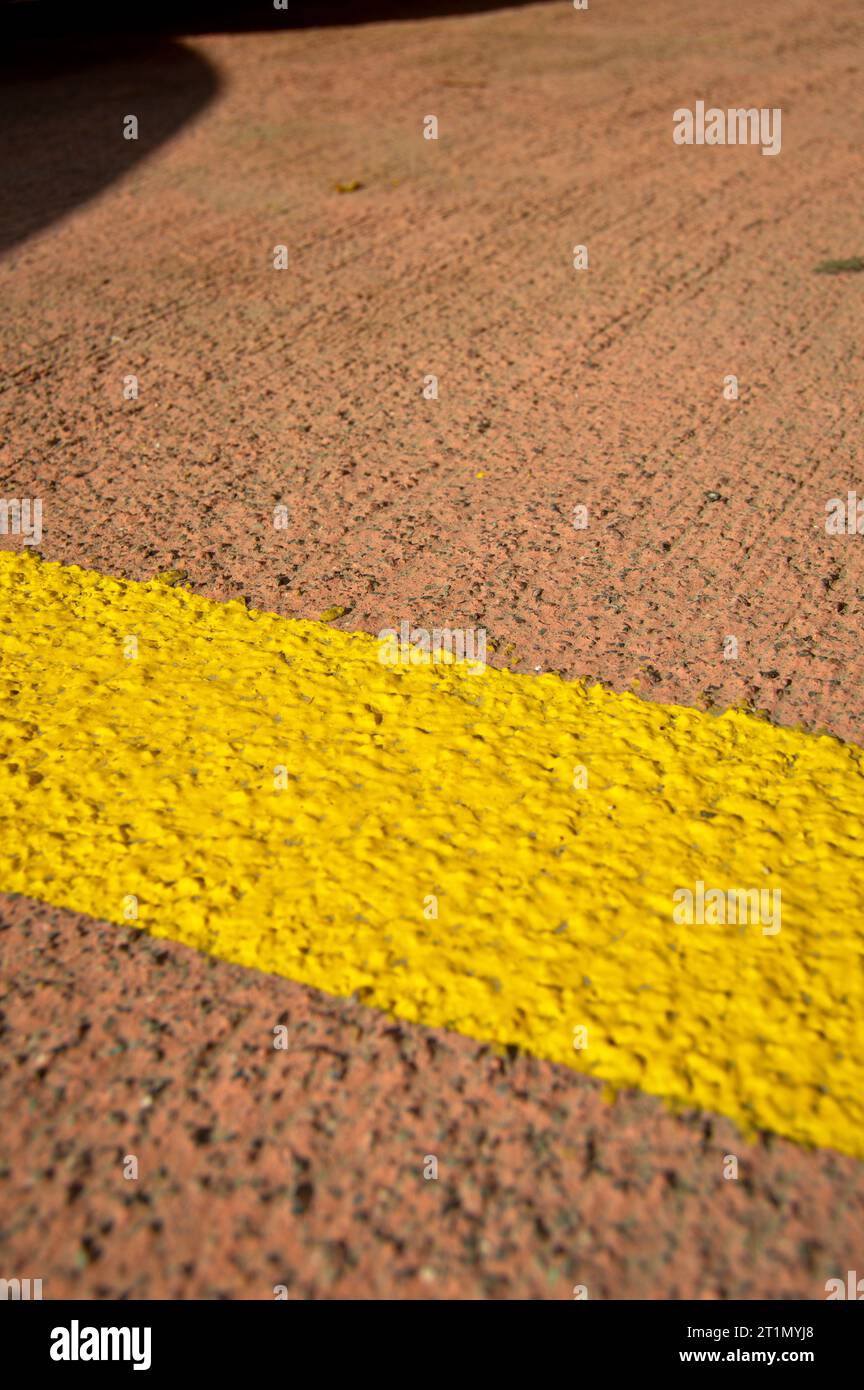 Red asphalt concrete road with yellow stripes and car parking area ...