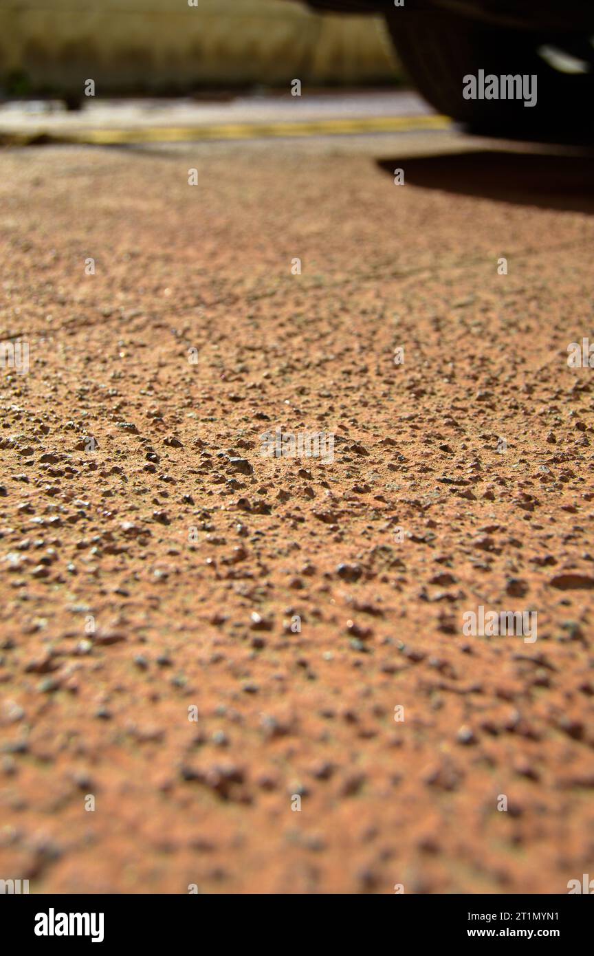 Red asphalt concrete road with yellow stripes and car parking area ...