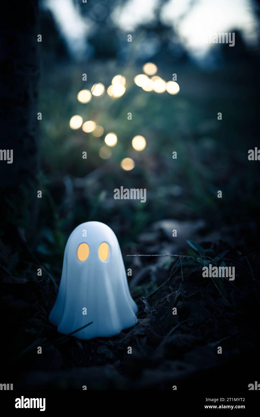 Ghost figurine or lamp with lit eyes glowing in outdoor setting, spooky ...
