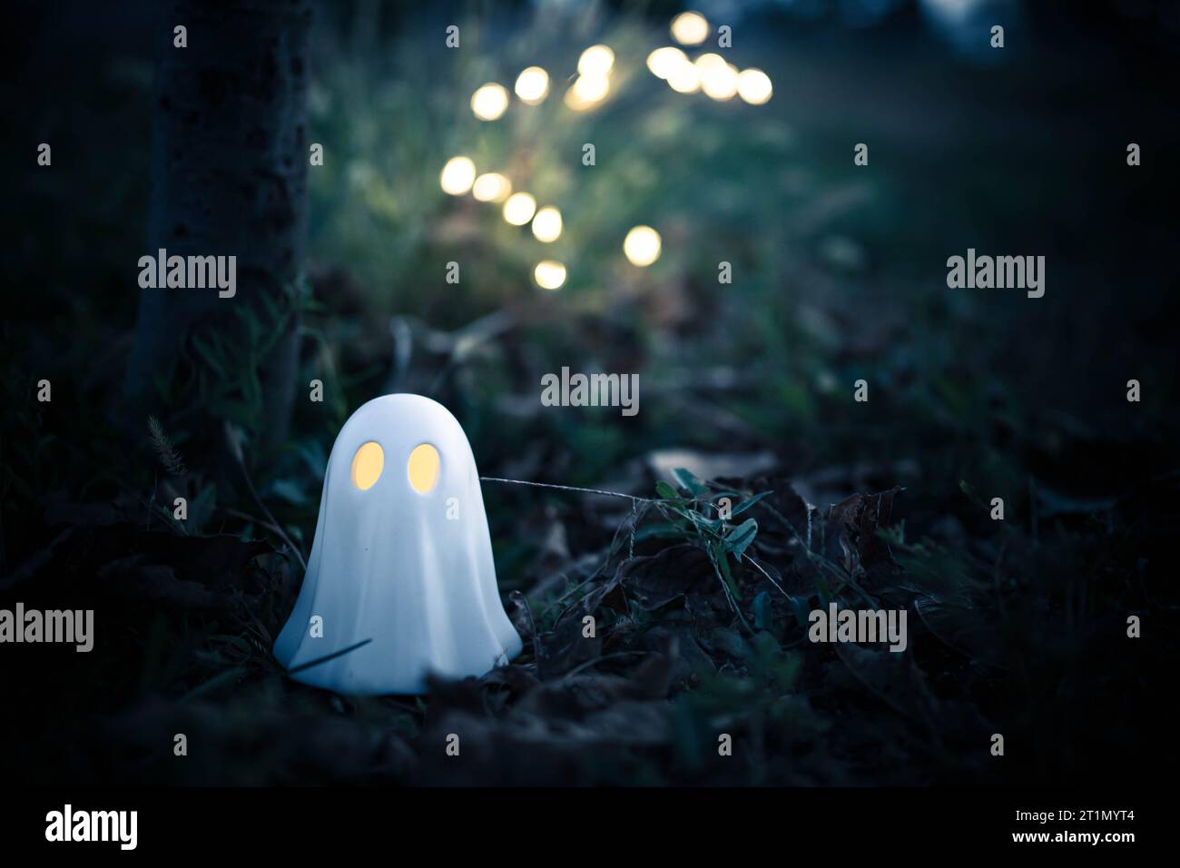 Ghost figurine or lamp with lit eyes glowing in outdoor setting, spooky ...