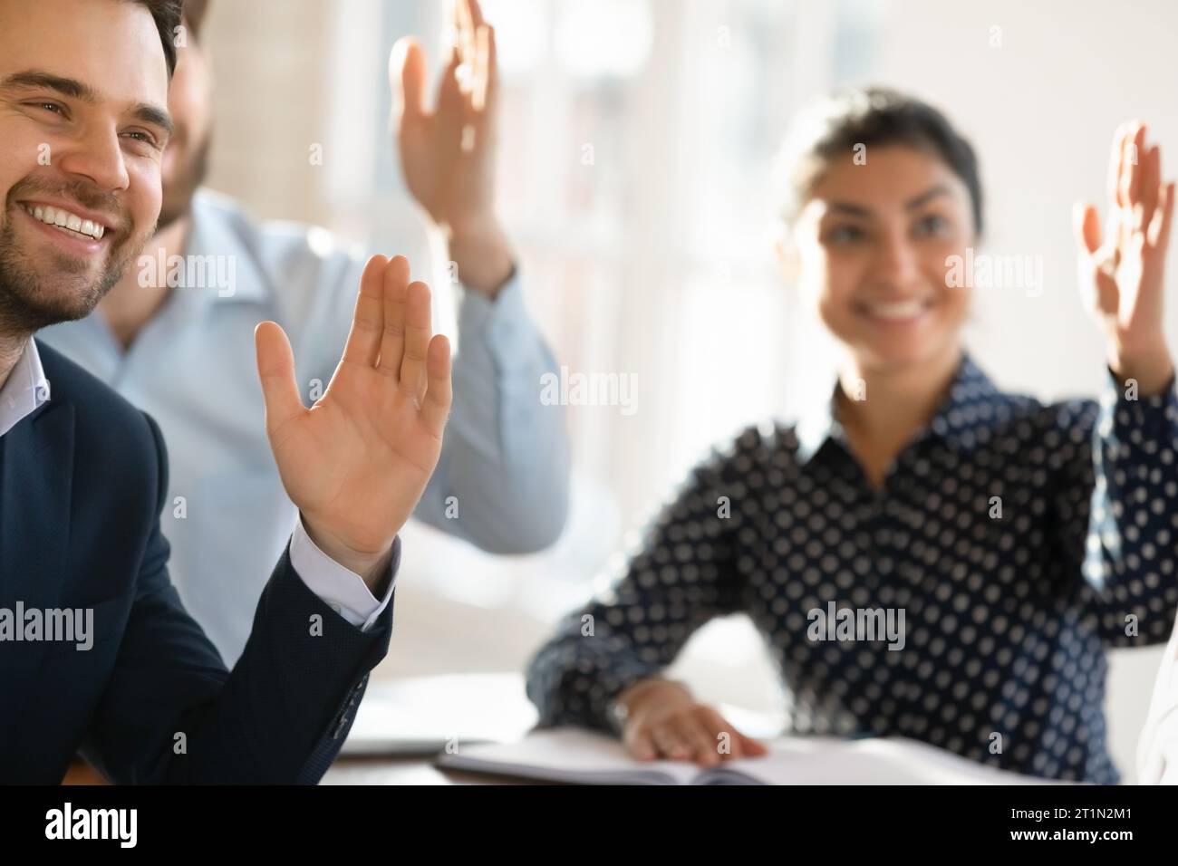 Positive motivated multiethnic business team voting with raised arms ...