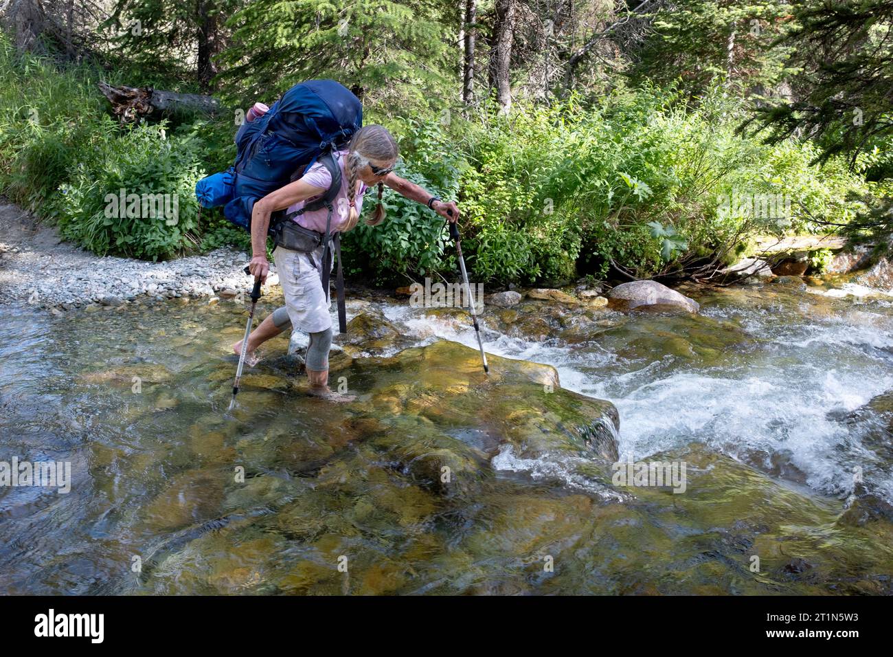 WY05483-00....WYOMING - Woman backpacker crossing a creek along the ...