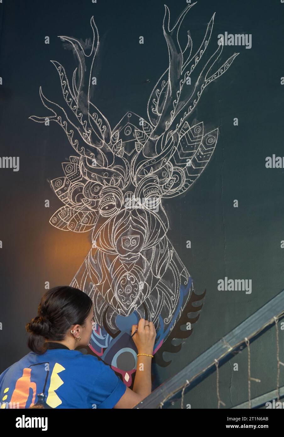Woman drawing a picture on the wall with a brush. Beautiful model woman ...