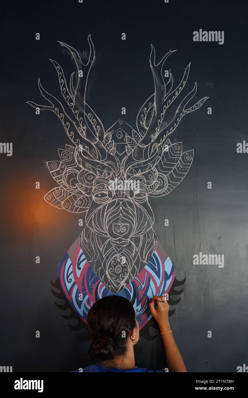 Woman drawing a picture on the wall with a brush. Beautiful model woman ...