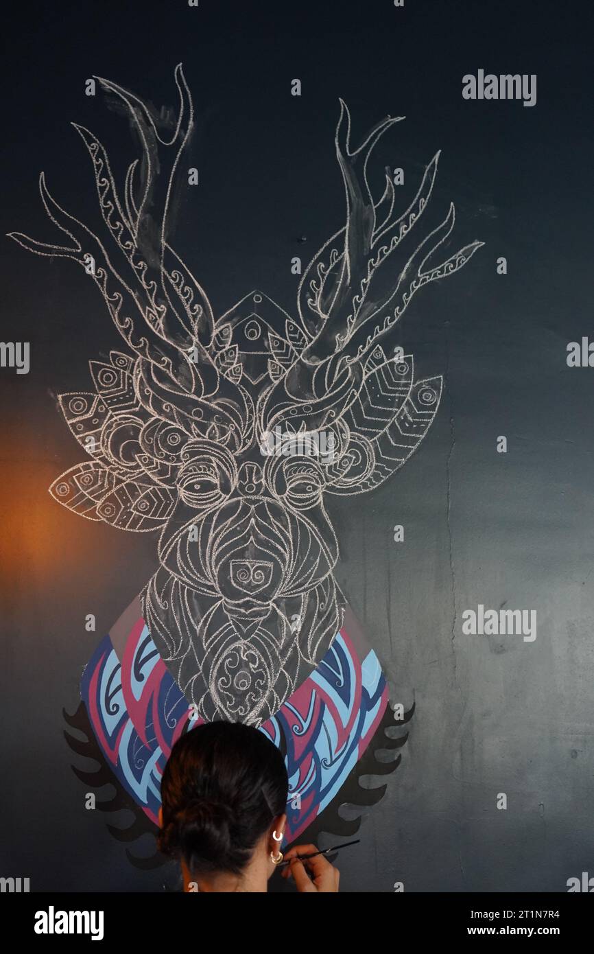 Woman drawing a picture on the wall with a brush. Beautiful model woman ...