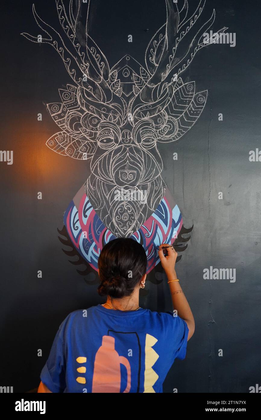 Woman drawing a picture on the wall with a brush. Beautiful model woman ...